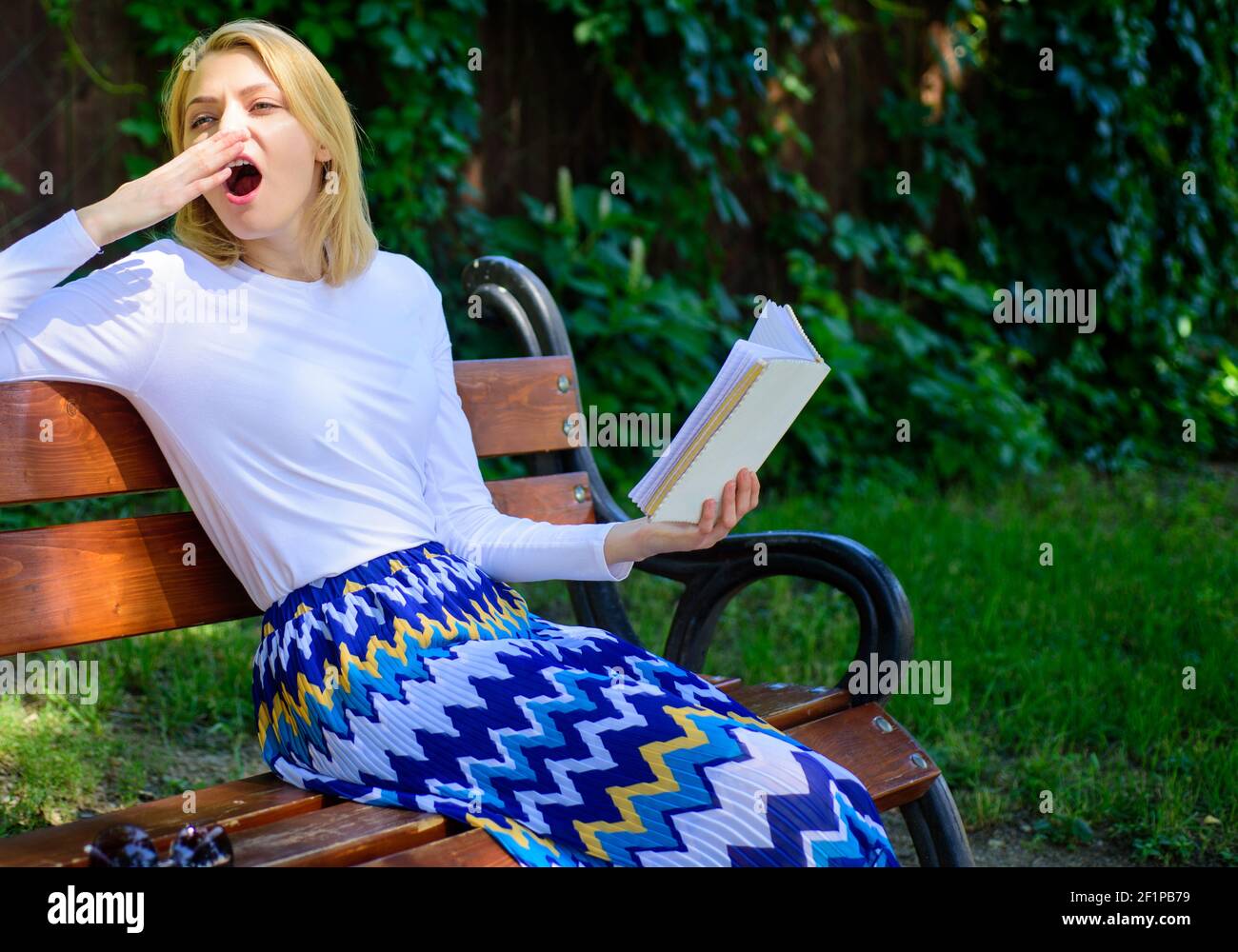 Boring literature. Woman yawning blonde take break relaxing in garden ...