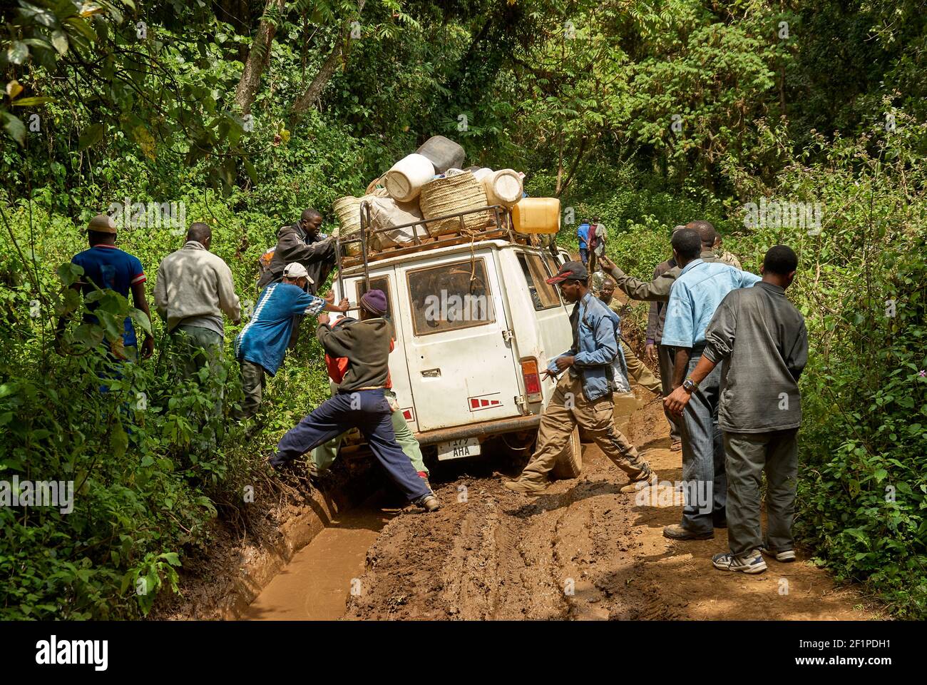 porters pushing heavy baggage loaded Minibus across a mud pool, Mount ...