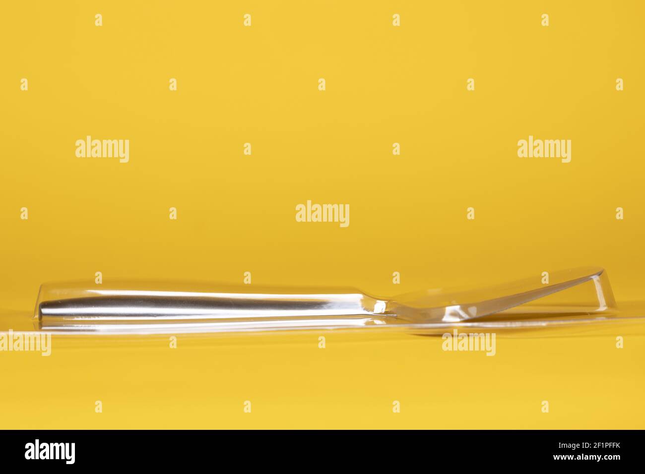 Cheese slicer laying flat under shiny plastic wrapper Stock Photo - Alamy