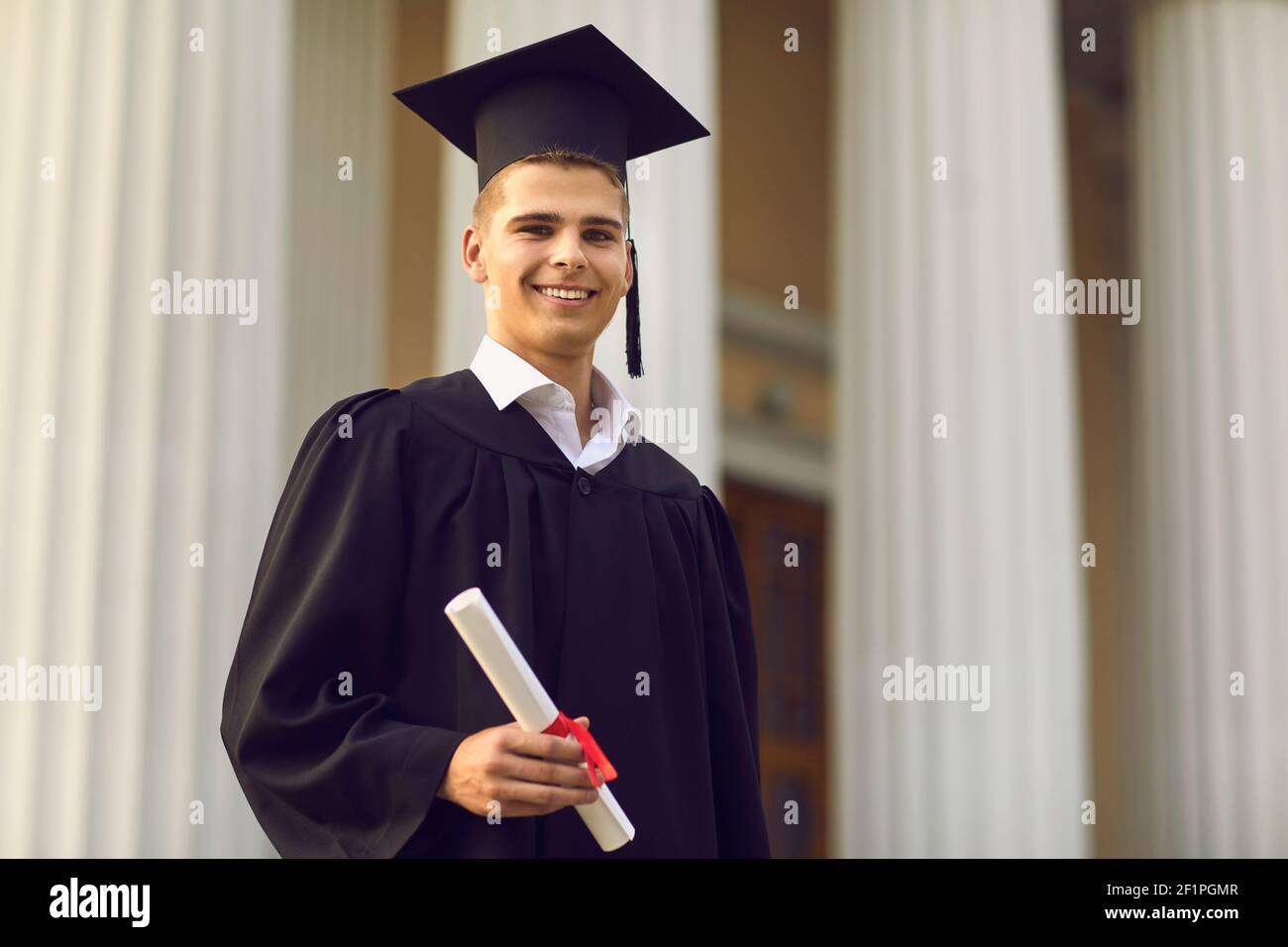 Young boy graduate standing with diploma in hand over university ...