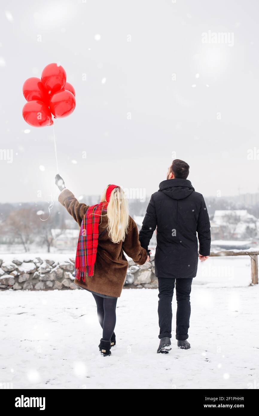 Young handsome guy and girl with a balloons walking on valentine's day ...
