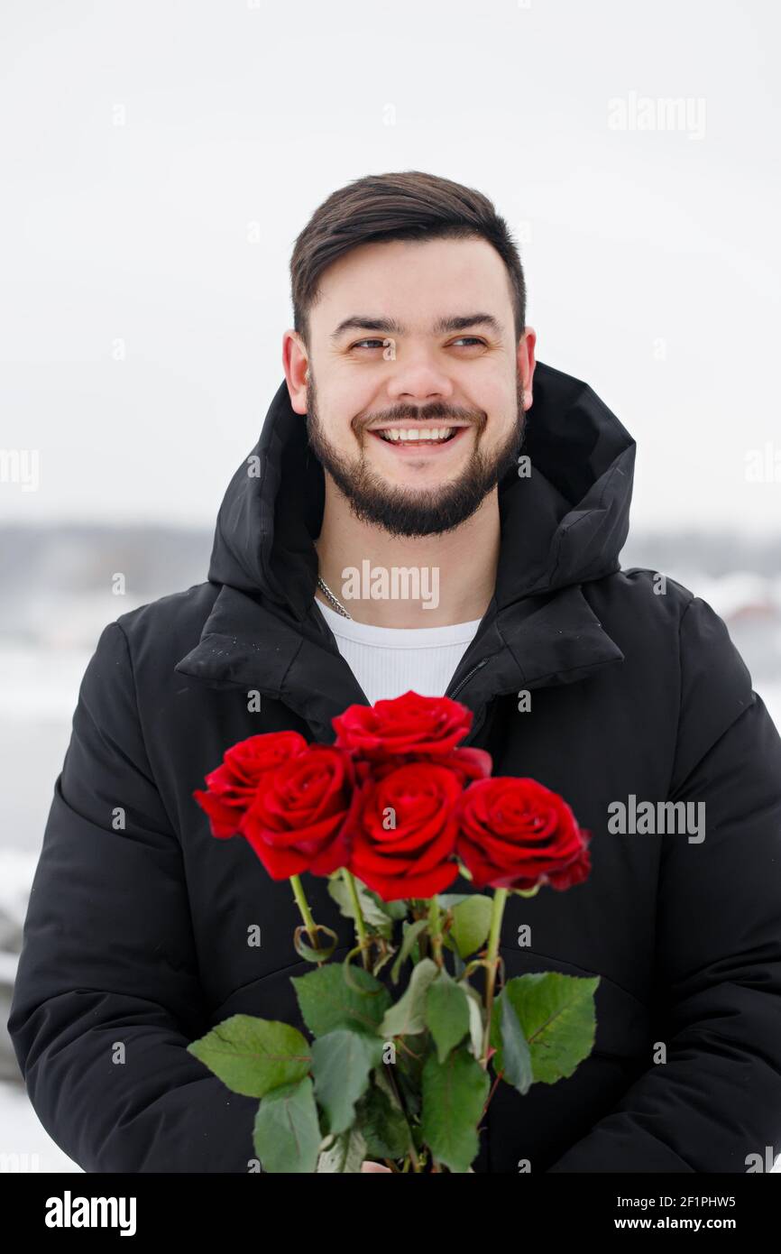 Handsome romantic young man with bouquet of red roses in hands Stock ...
