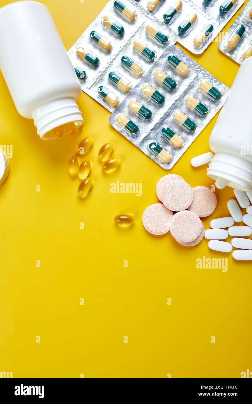 Flat lay of pills, fish oil, vitamins on yellow background, Healthcare ...