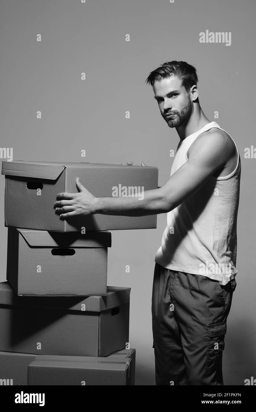 Guy stands among boxes,copy space. Man with beard stands dark grey ...