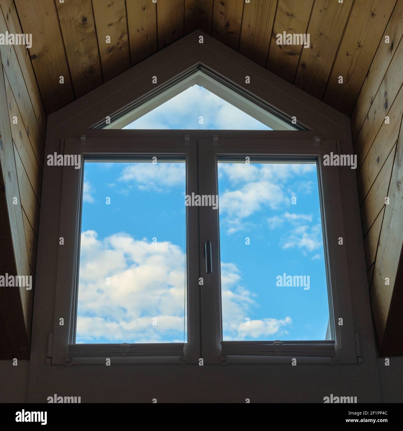 Blue sky and white clouds seen through a large dormer window in a ...
