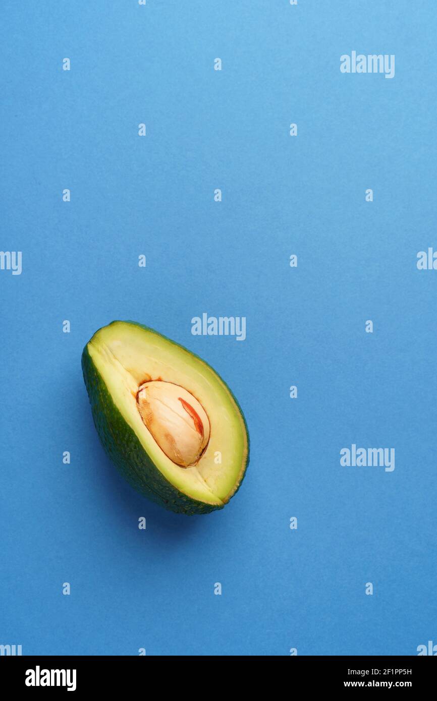 Half an avocado on a blue background. Minimalism and objects on a ...