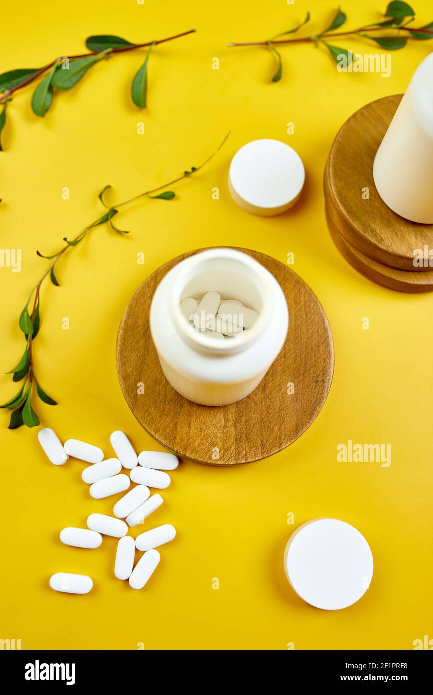 Flat lay Organic medical pills with herbal plant on a yellow background ...
