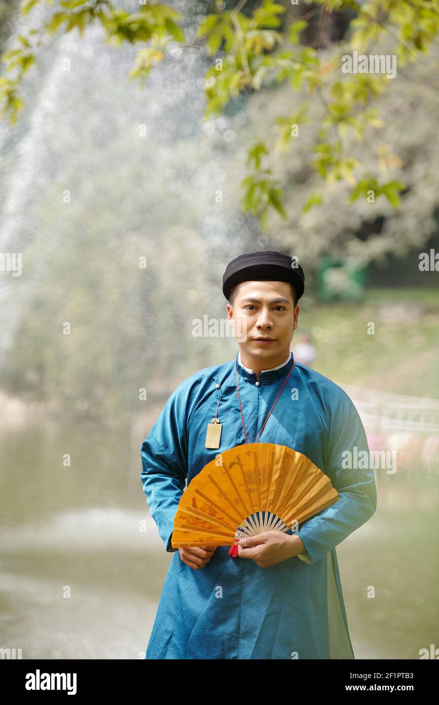 Portrait of handsome young Vietnamese man in ao dai dress and ...
