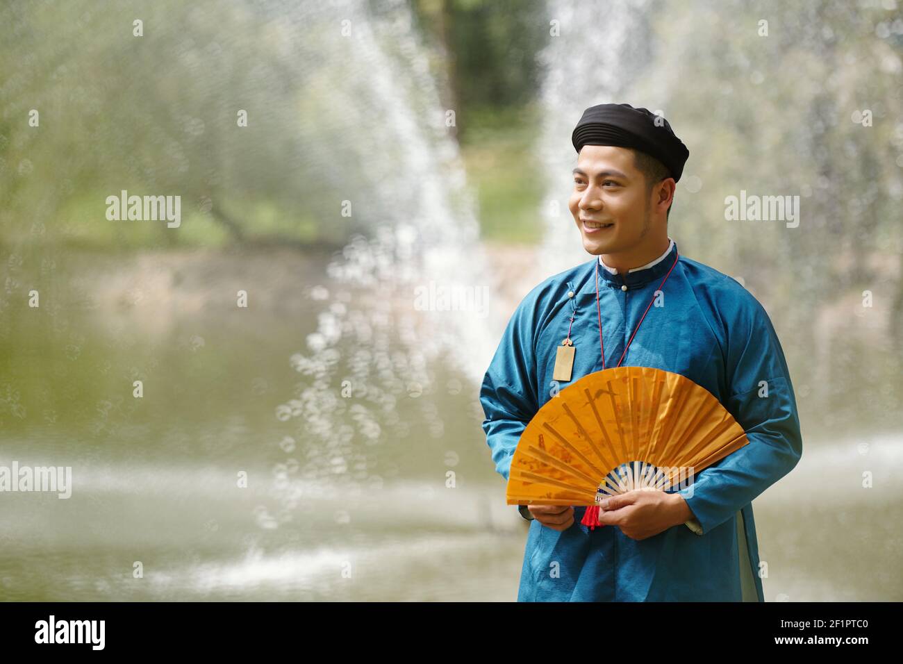 Happy young Asian man in traditional Vietnamese costume and headpiece ...