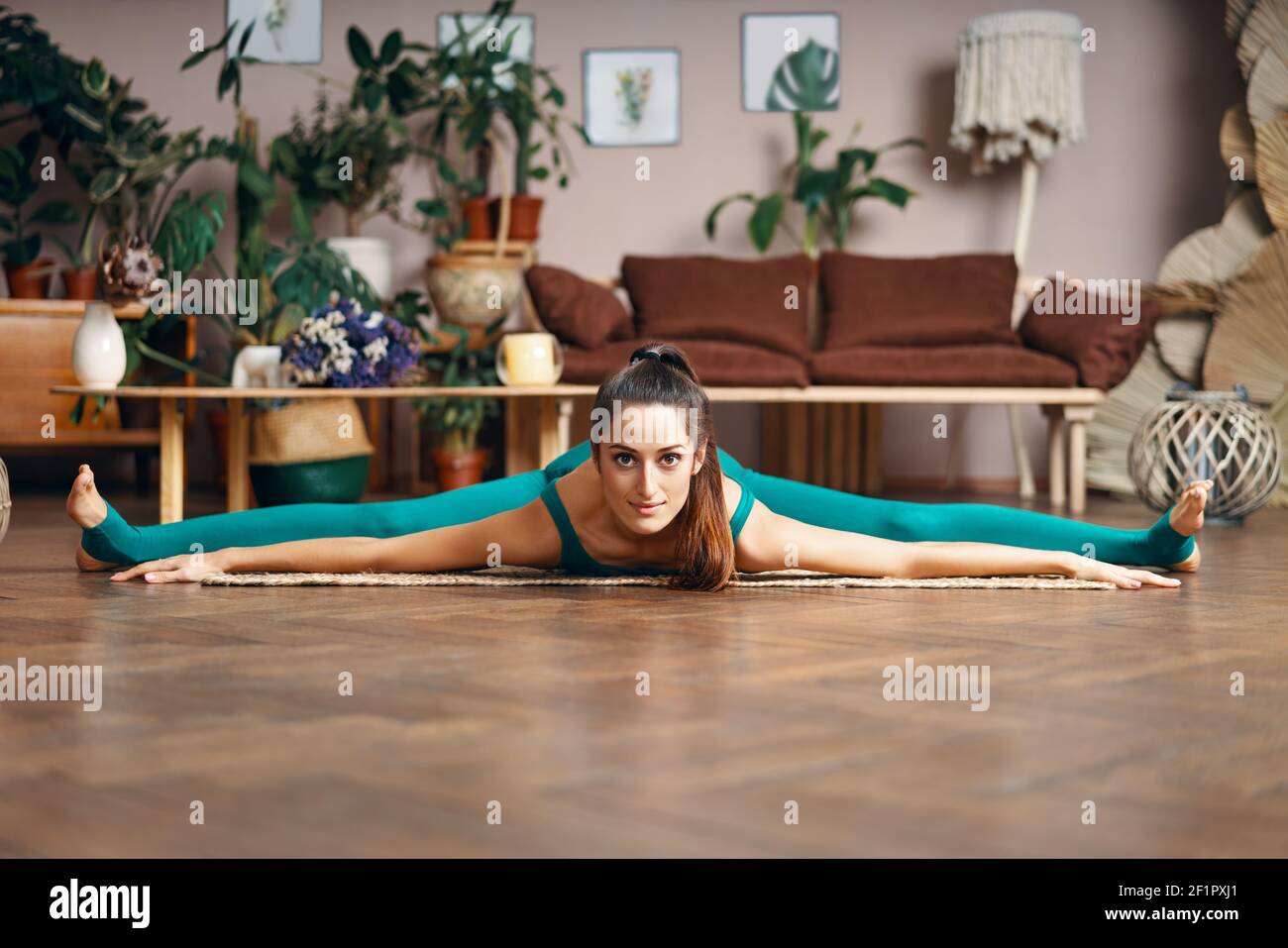 Young sporty woman practicing yoga at home doing stretching exercise ...