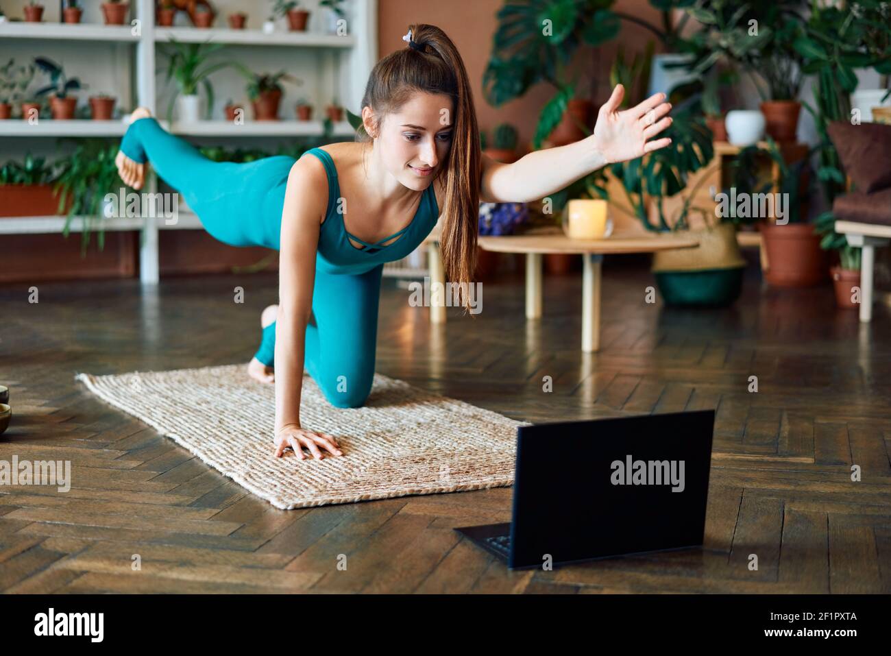 Young sporty woman practicing yoga at home watching online exercises on ...