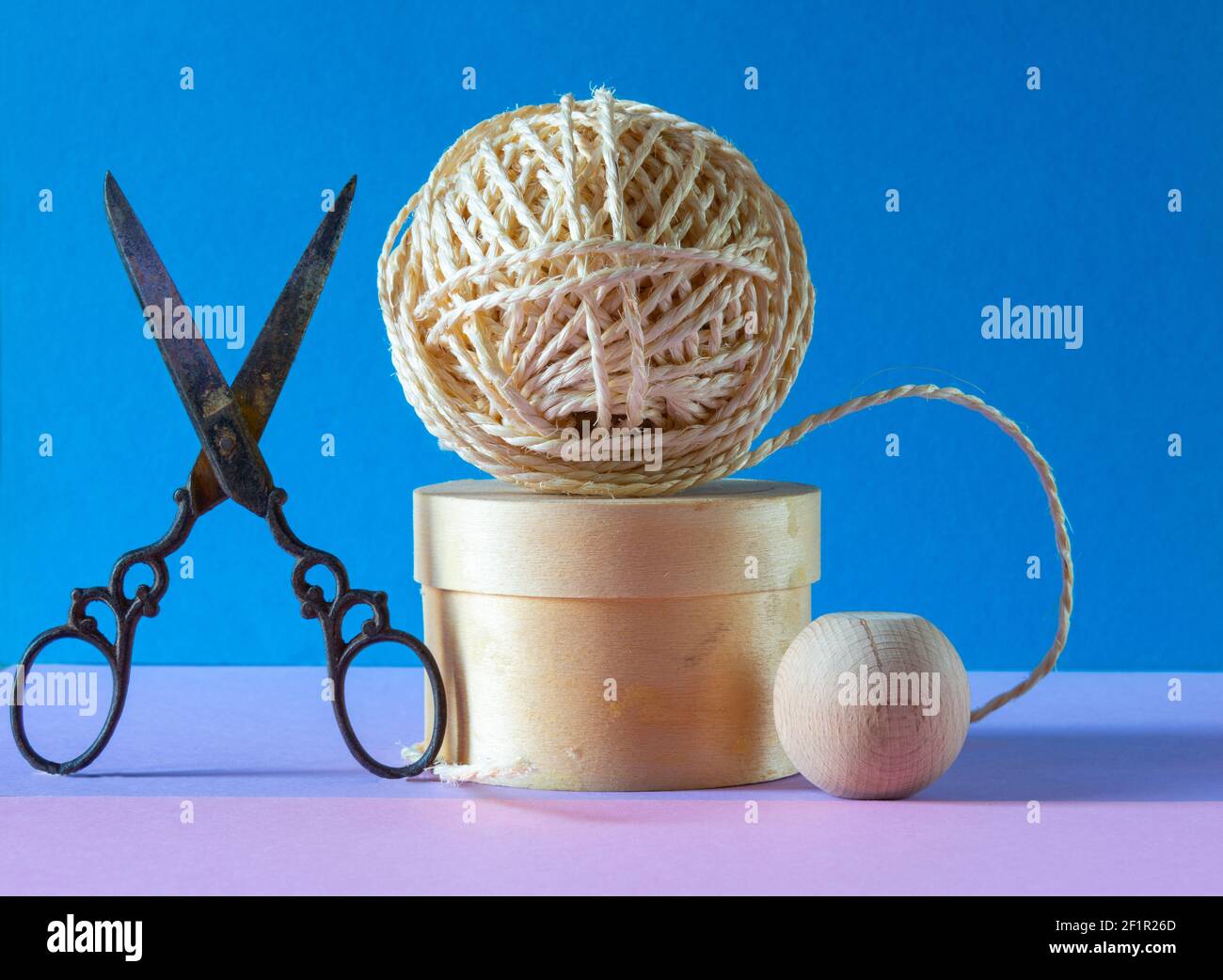 ball of string on a wooden pedestal with a pair of ornate scissors on a ...