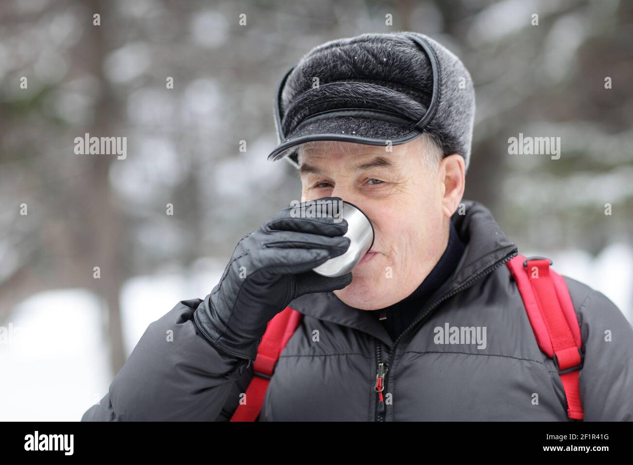 Senior man drinking tea in the winter park Stock Photo - Alamy