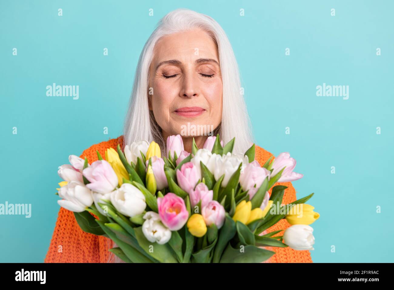 Photo of peaceful charming elderly woman smell flowers tulips wear ...