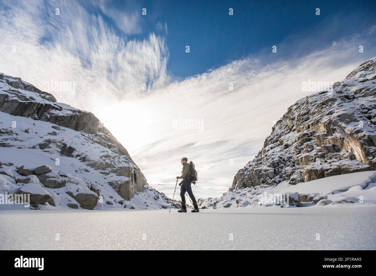 Backpacker traverses winter landscape between two mountains Stock Photo ...