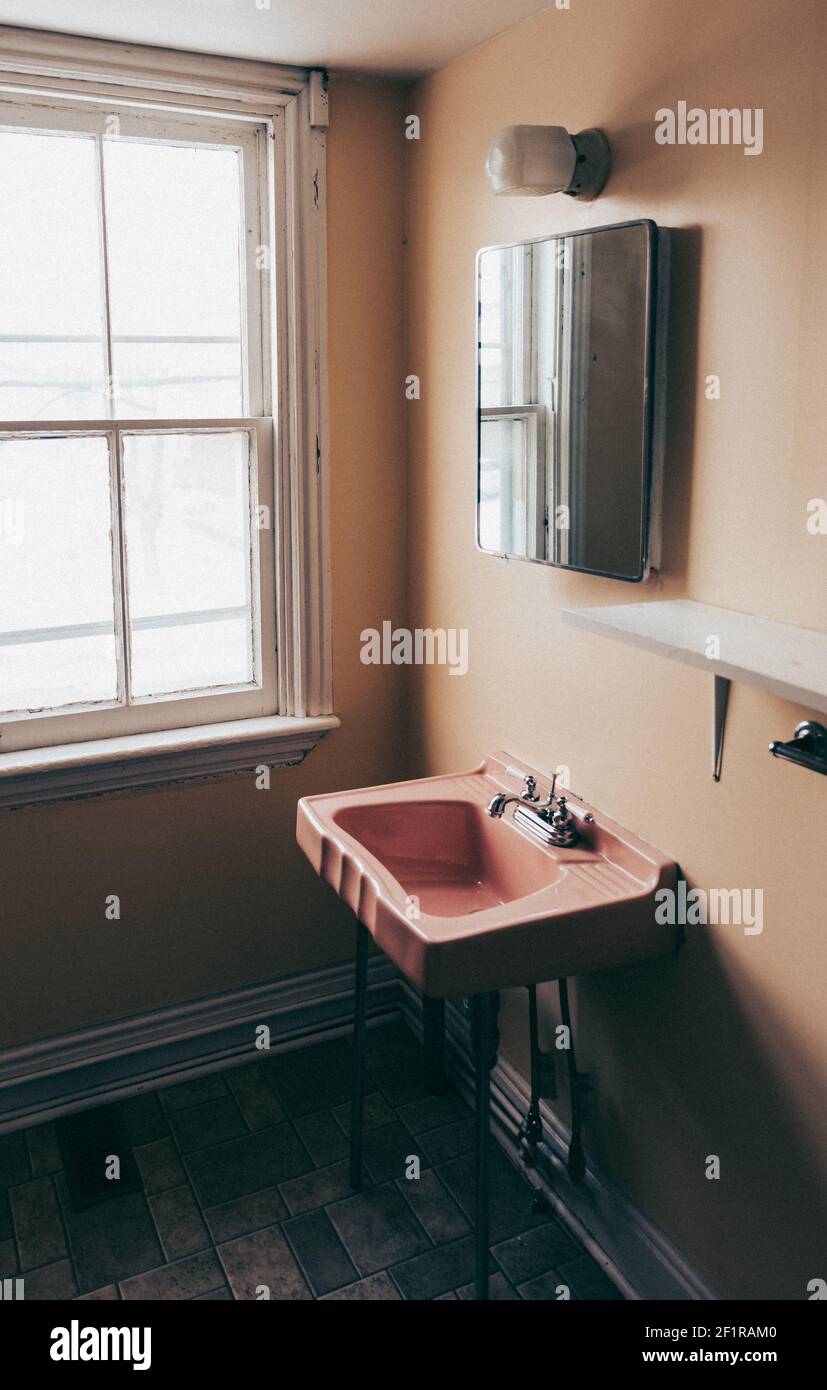 Retro vintage pink sink an mirror in an old empty dingy bathroom Stock ...