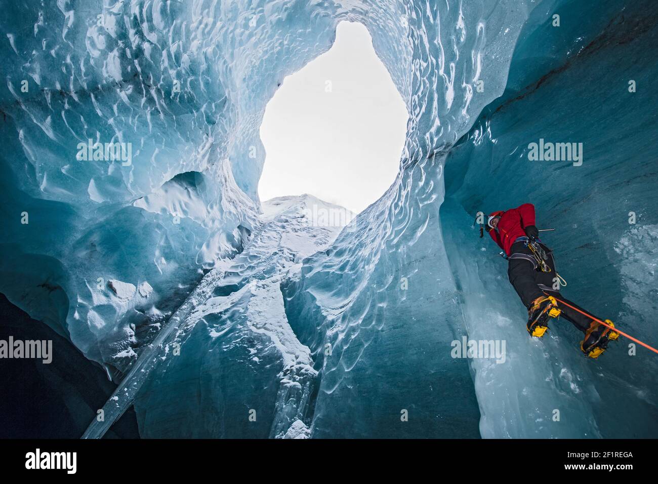 man climbing icicle inside glacier cave in Iceland Stock Photo - Alamy