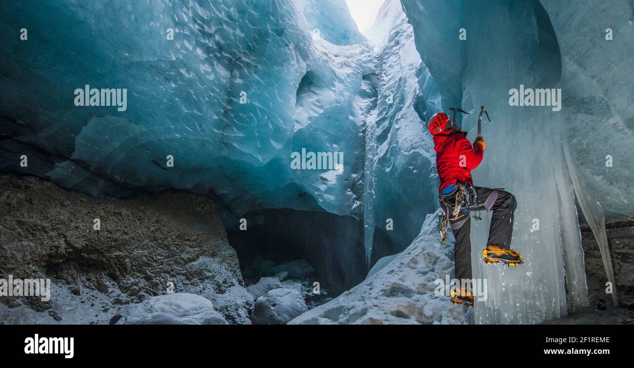 man climbing icicle inside glacier cave in Iceland Stock Photo - Alamy