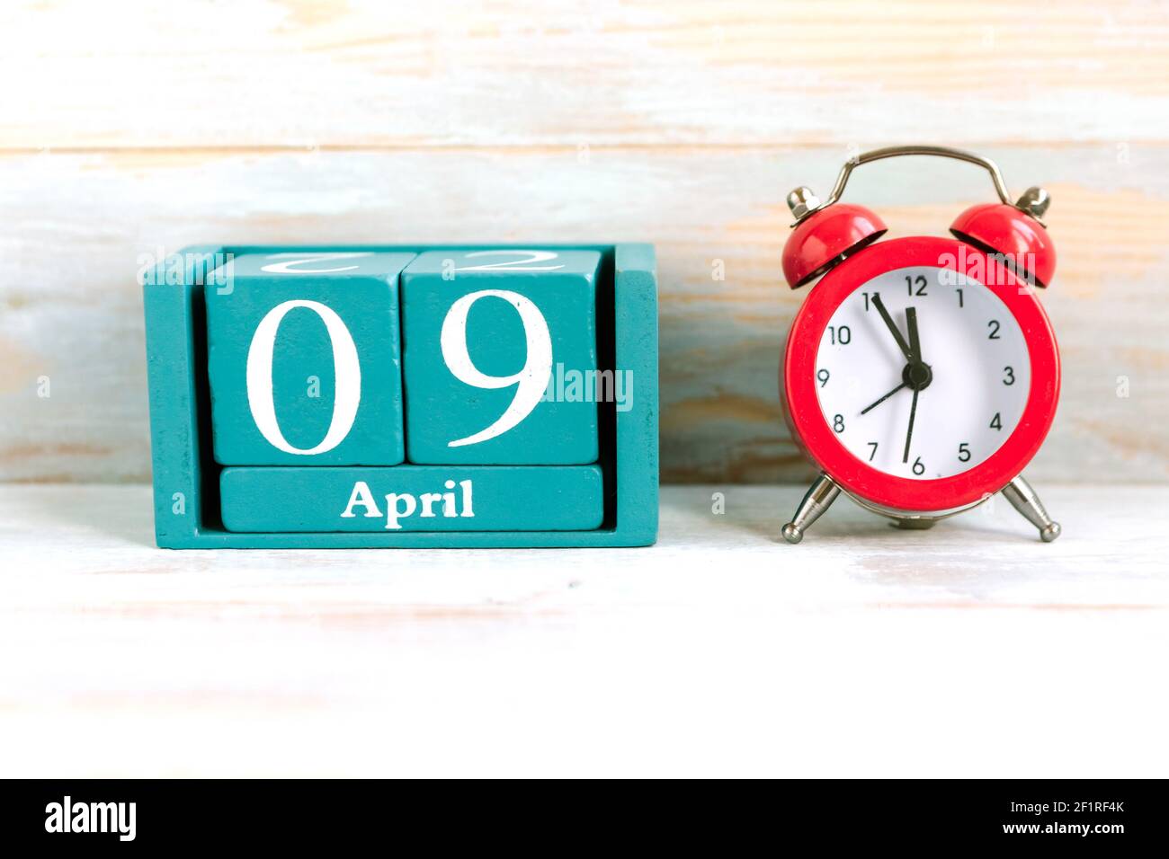 April 9. Blue cube calendar with month and date on wooden background ...