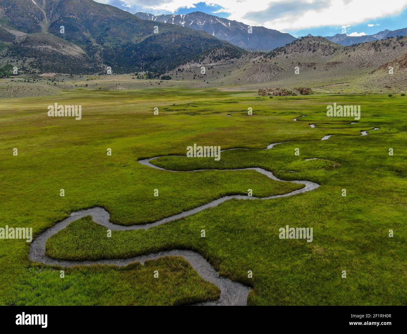 Aerial view of green land and small curve river with mountain in the ...
