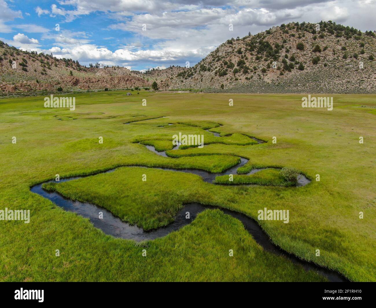 Aerial view of green land and small curve river with mountain in the ...