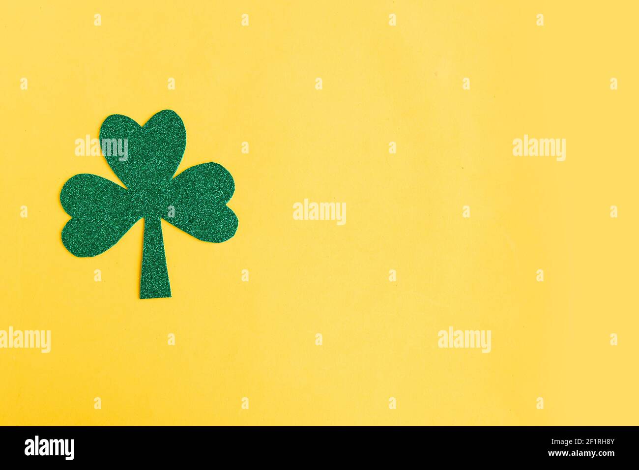 Green shamrock isolated on bright yellow background. Three leaf clover ...