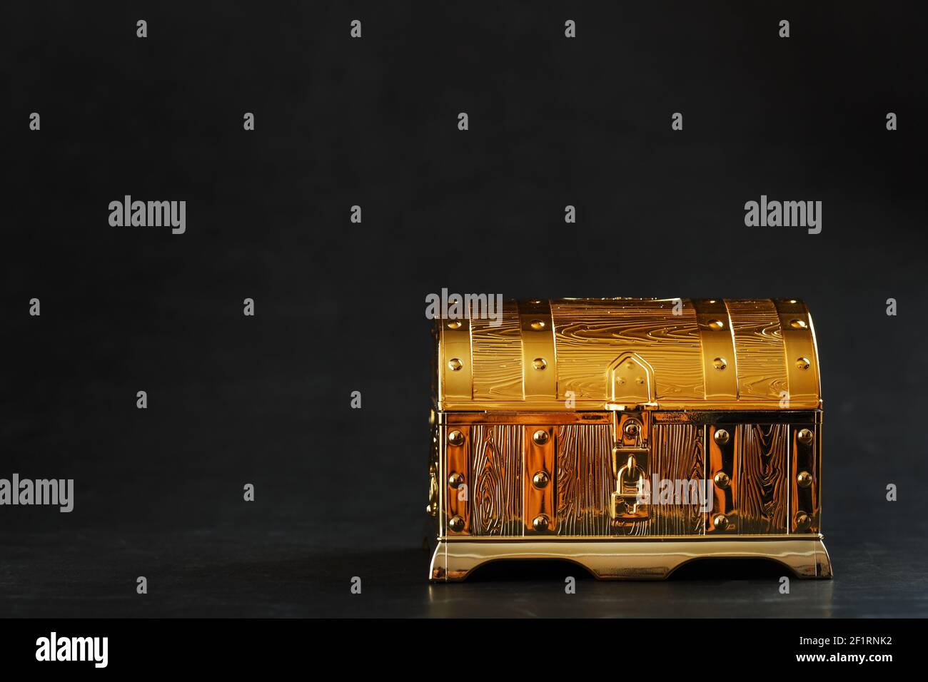 A chest made of gold with jewels on a black background. Free space, the ...