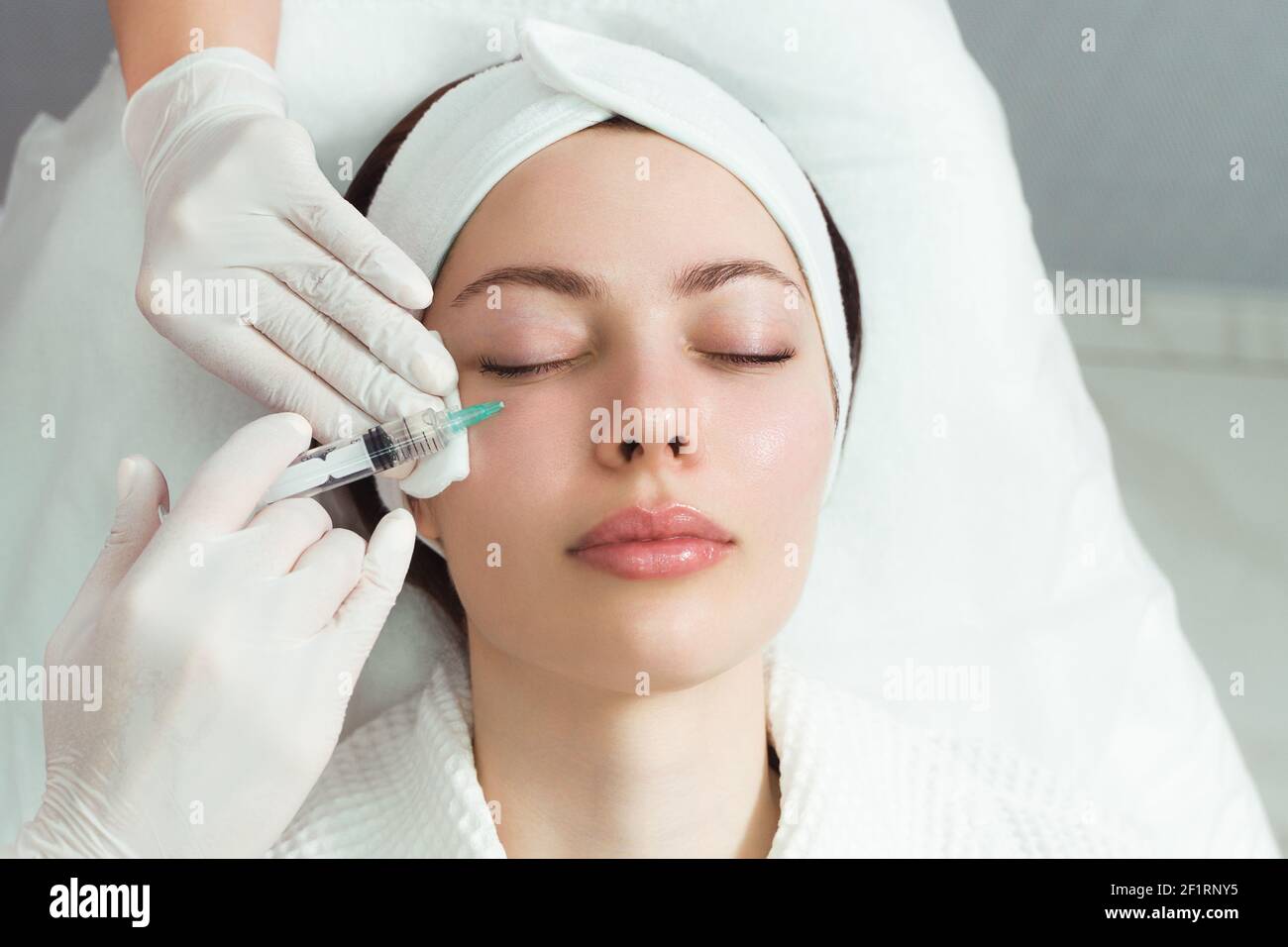 The doctor cosmetologist makes the rejuvenating facial injections ...