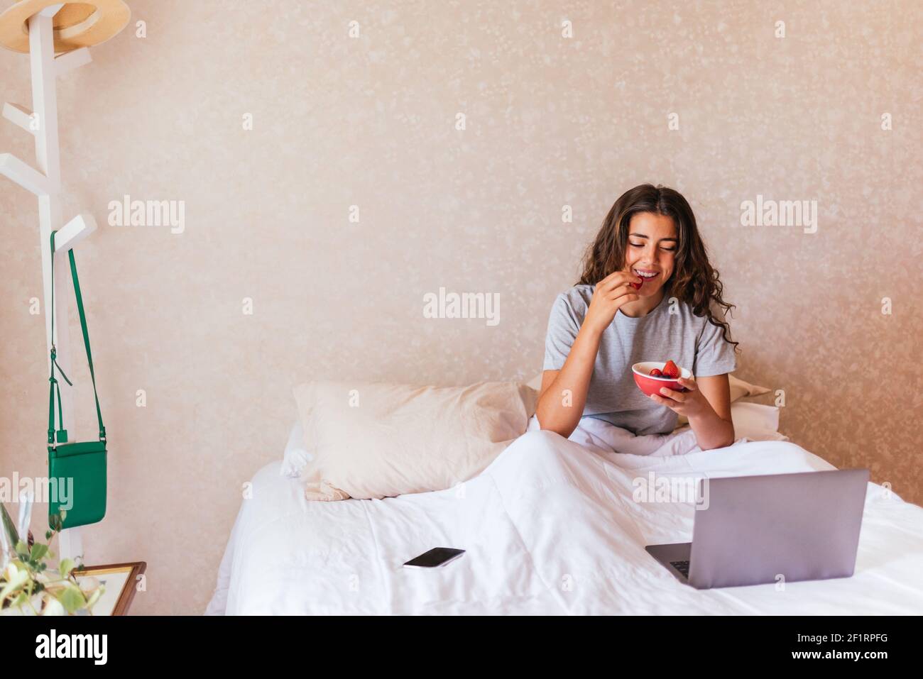 Stock photo of happy girl in pajamas using computer in the bed and ...