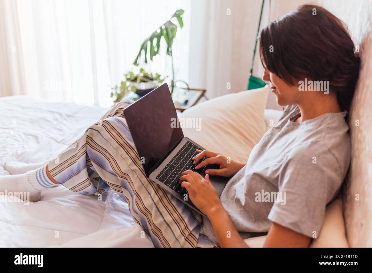 Stock photo of happy girl in pajamas using computer in the bed and ...
