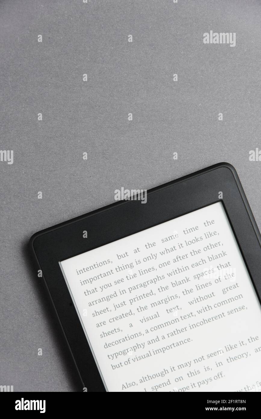 Closeup image of an electronic reader with text on the screen on a grey ...