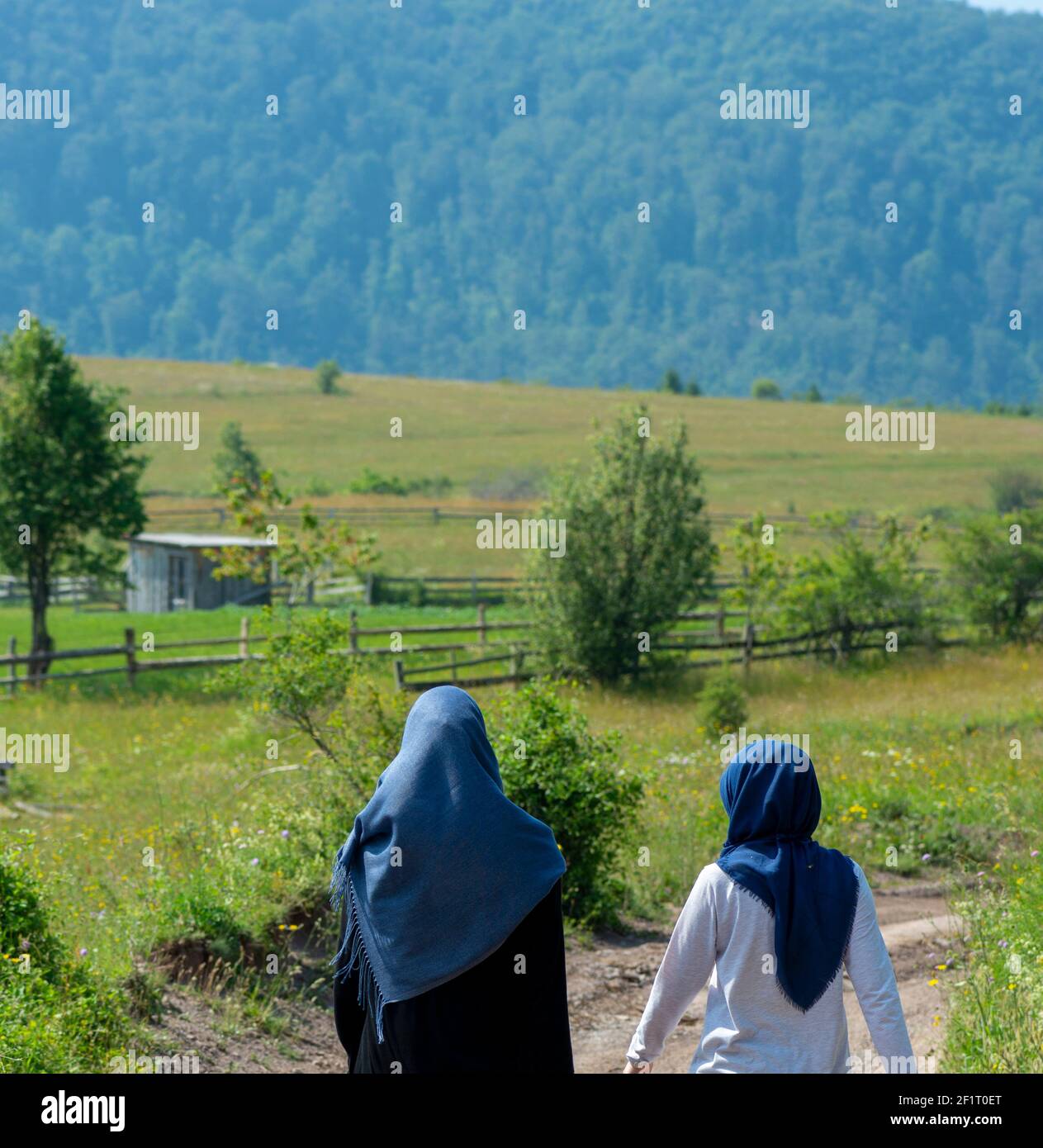 Two muslim girls walking on the rural mountain road with beautiful ...