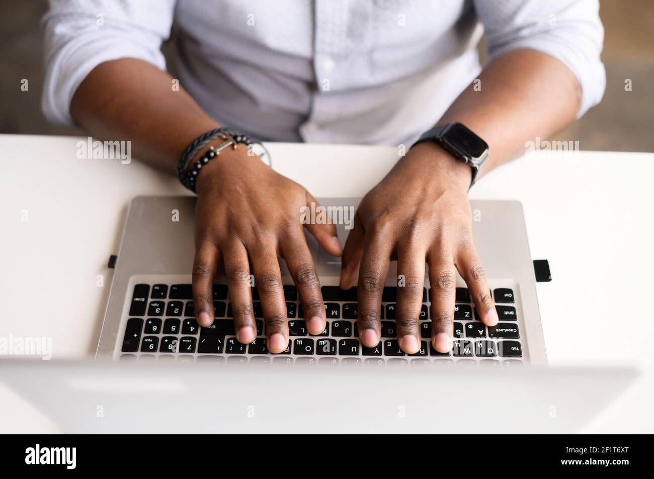 A male hands on the laptop keyboard. Top view an African-American guy ...