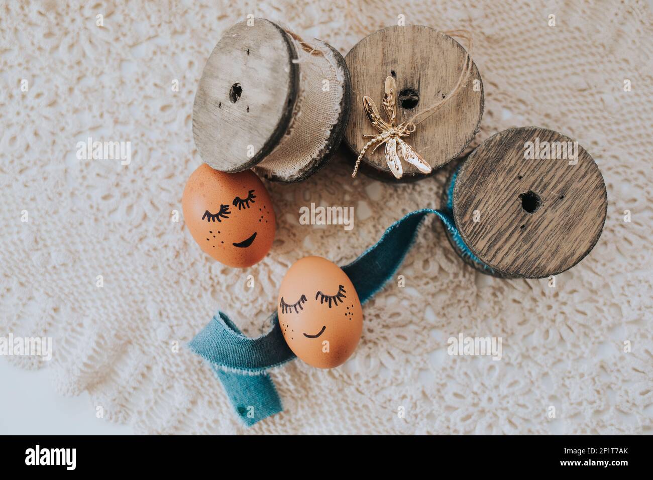 A top view of two decorated Easter eggs and wooden threads on a fabric ...