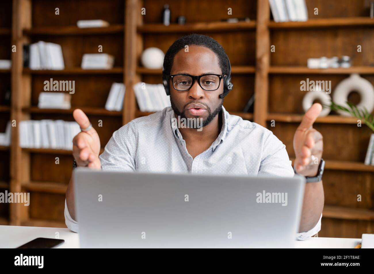 Focused African-American man is call center worker or support customer ...