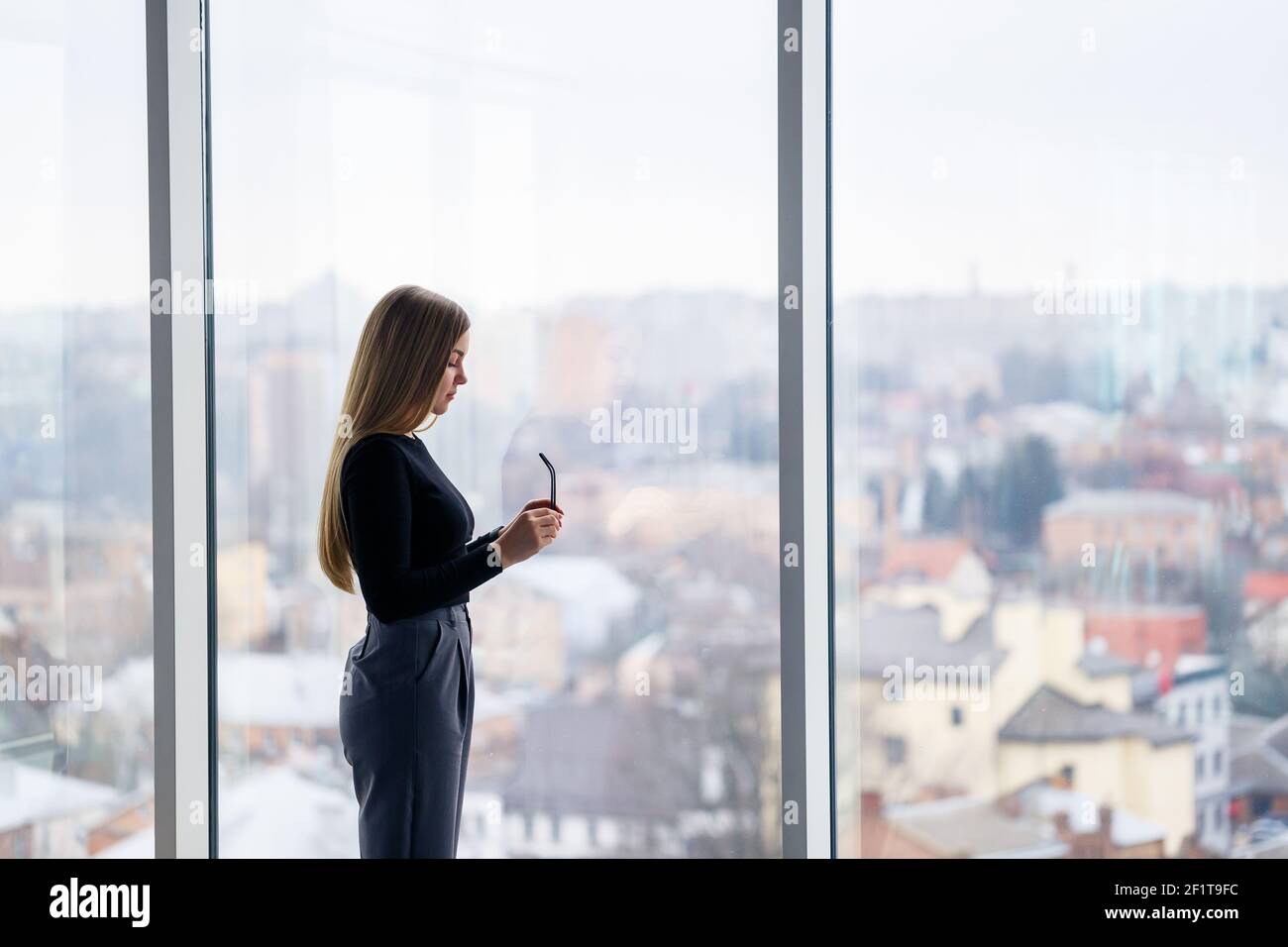 A successful female manager in her own office with large windows is ...