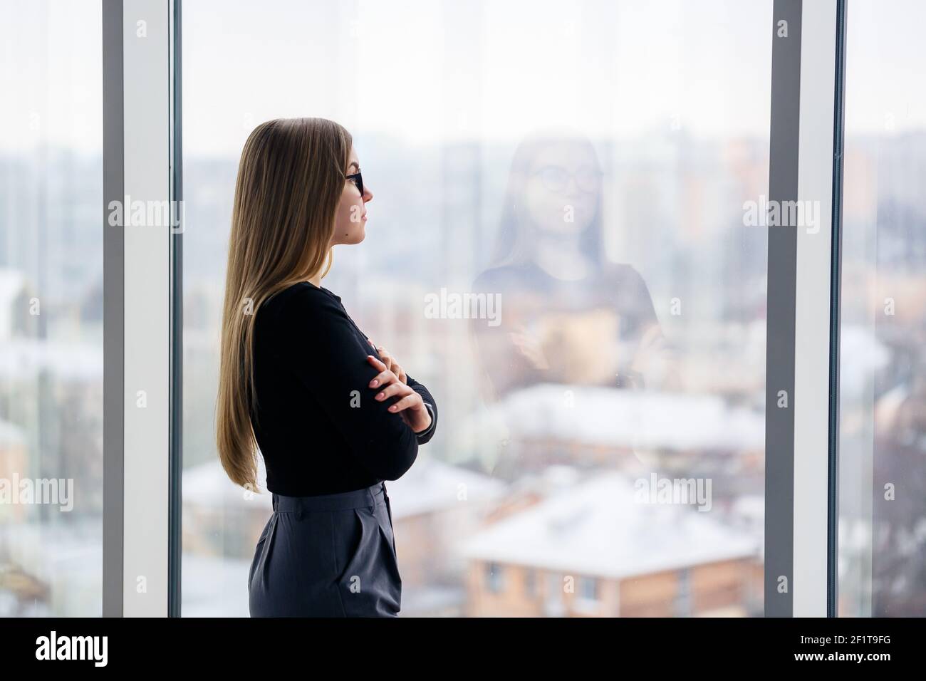 A successful female manager in her own office with large windows is ...