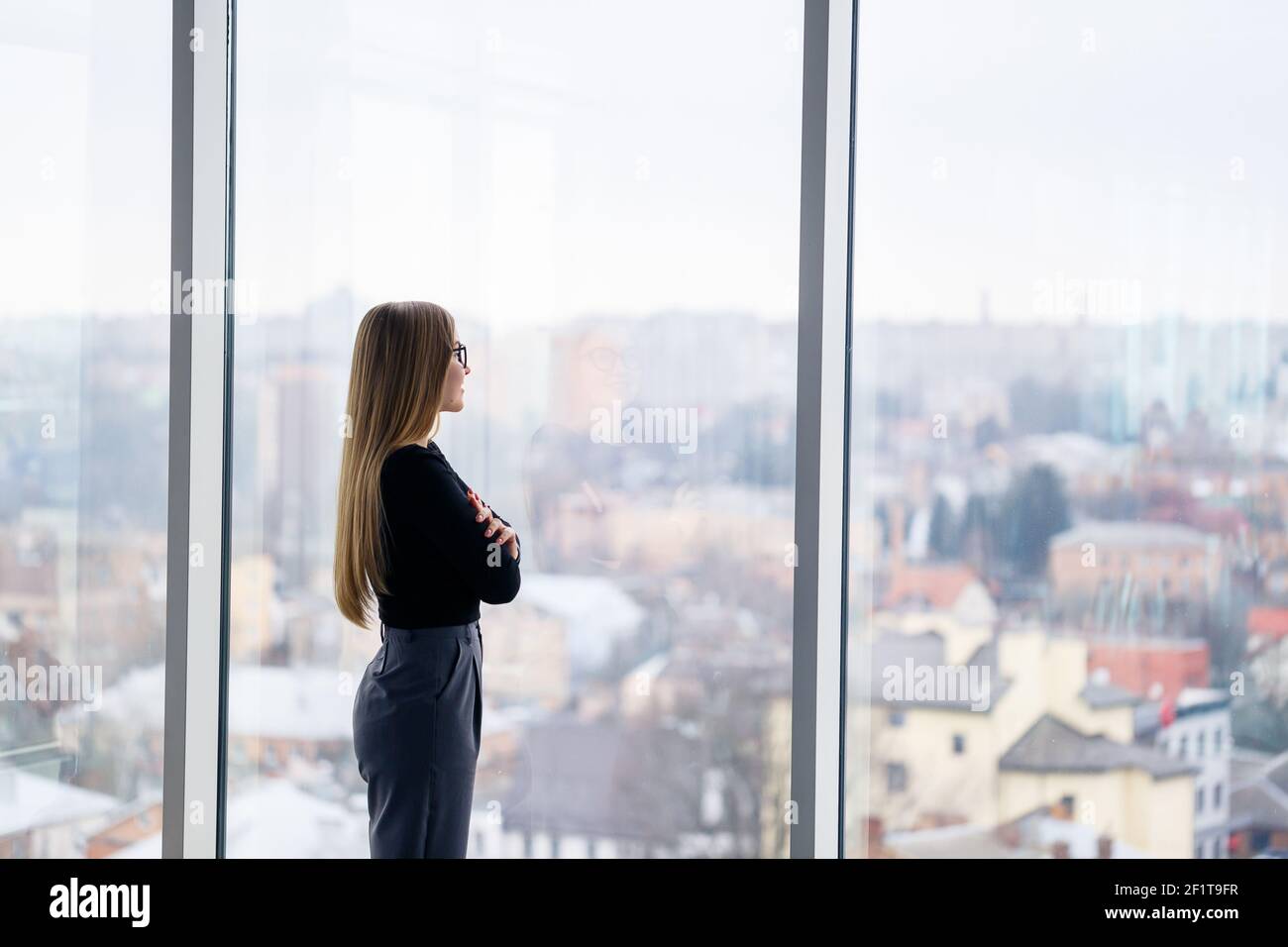 A successful female manager in her own office with large windows is ...
