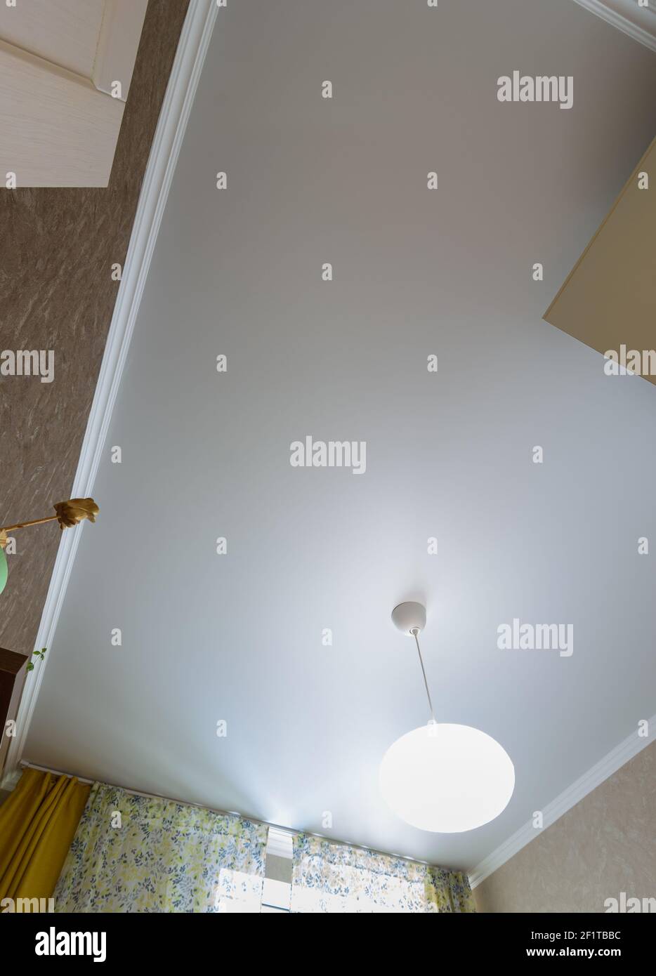 Stretch white matte ceiling with a chandelier in the interior of a ...