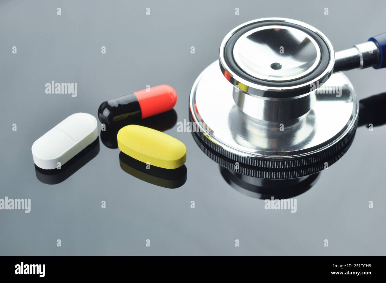 Stethoscope and Medication on a glossy black surface. Diagnosic and ...