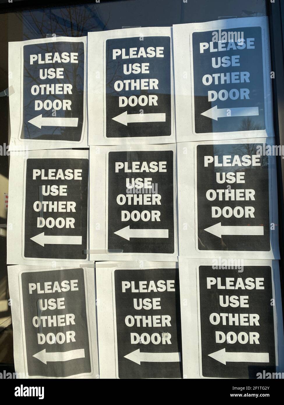 "Please use other door" sign in an entry door window to keep the flow ...