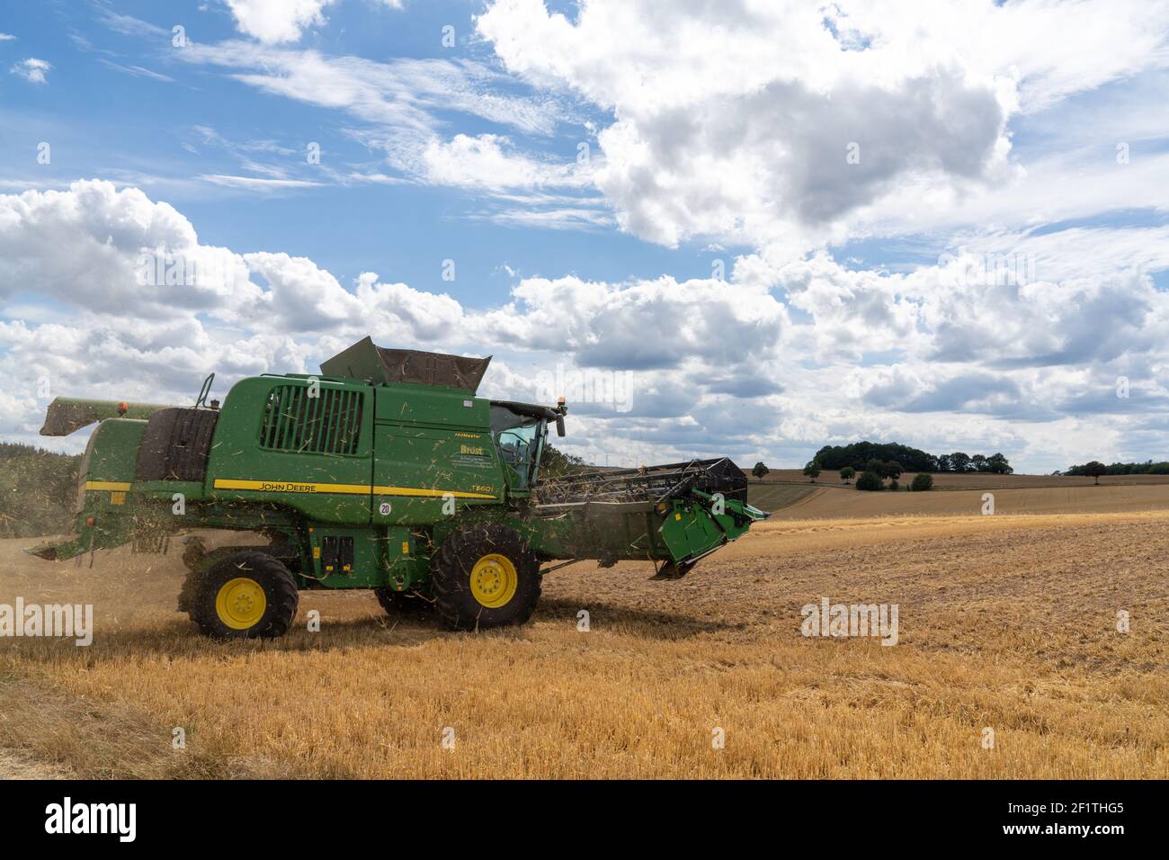 A green combine harvester unloading cut wheat crop into a tractor ...