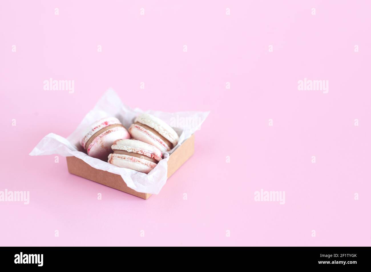 Tasty french macaroons in a box on a pink pastel background. Place for ...