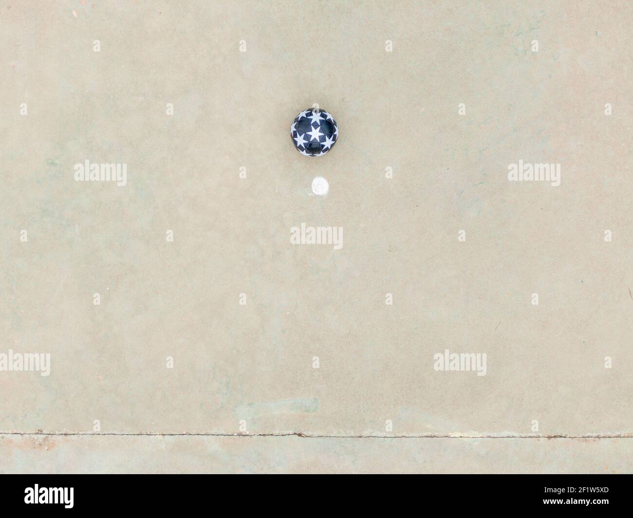 top view of a ball on the ground of a sports court with a concrete ...