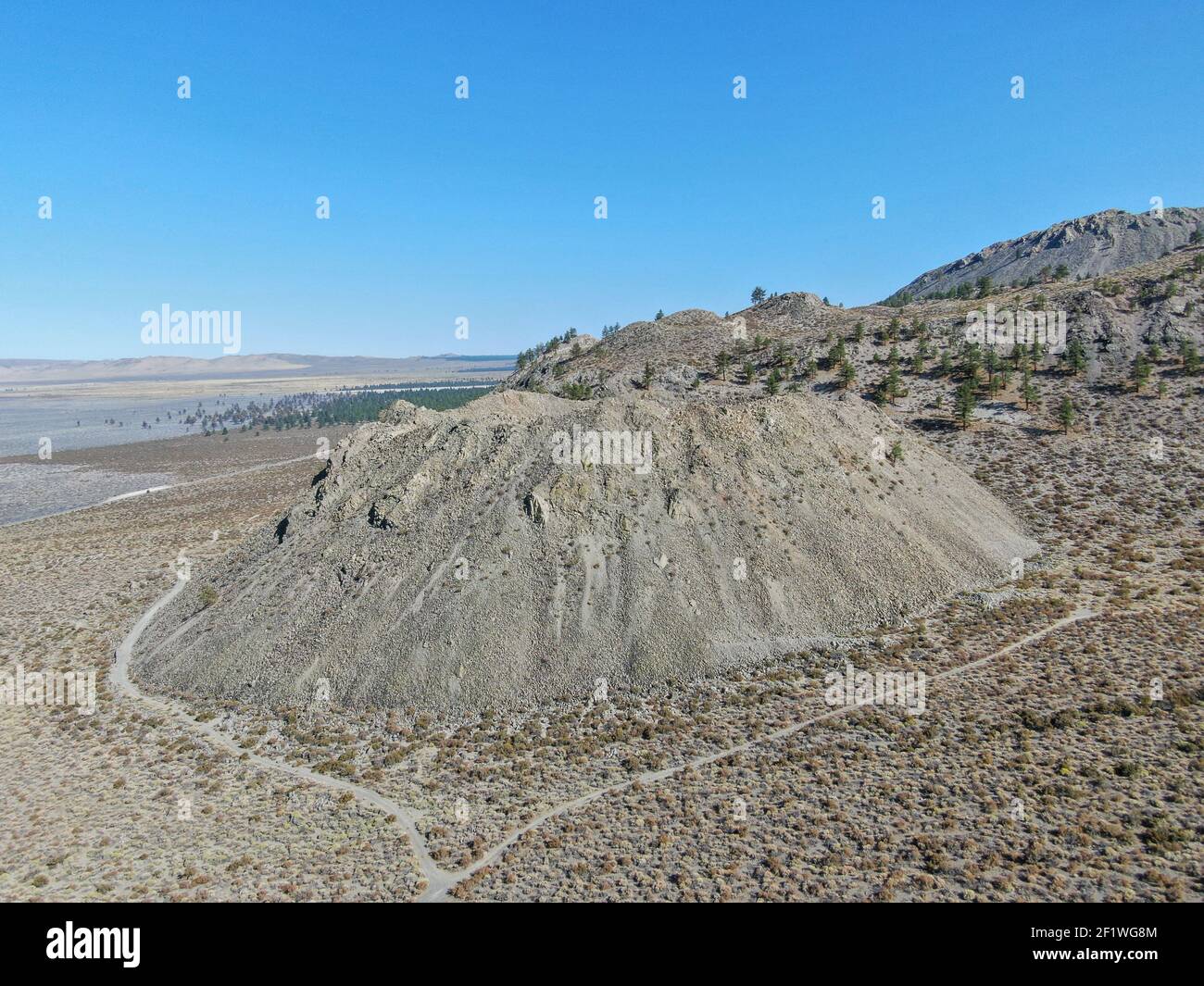 Aerial view of dusty dry desert land and mountain on the background in ...