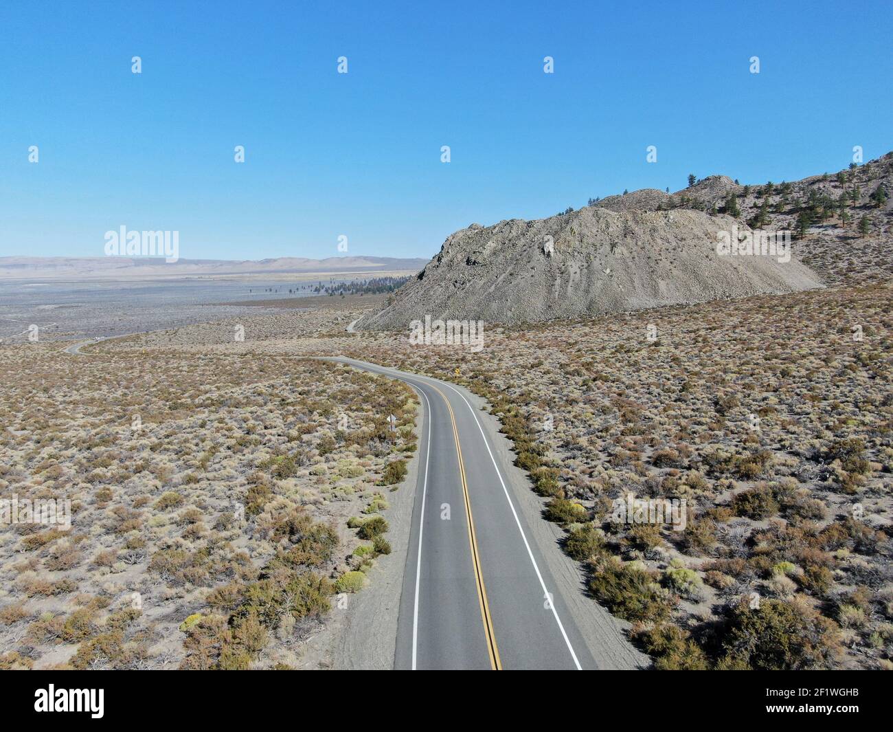 Aerial view of asphalt road in the middle of dusty dry desert land in ...