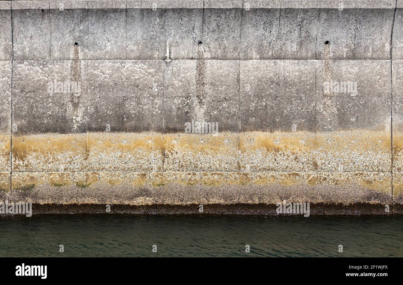 A decades old, concrete wall in Ibusuki harbor, shows sings of the ...