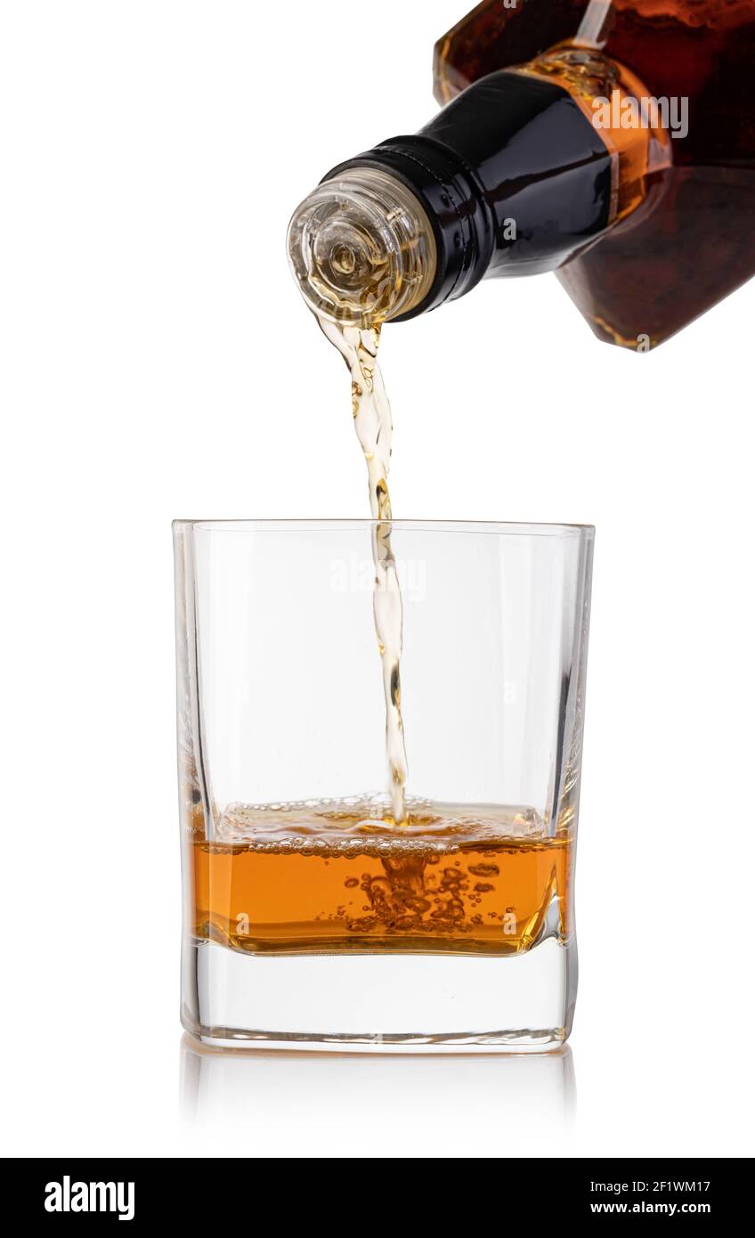 Whiskey poured into a glass from a bottle Stock Photo - Alamy
