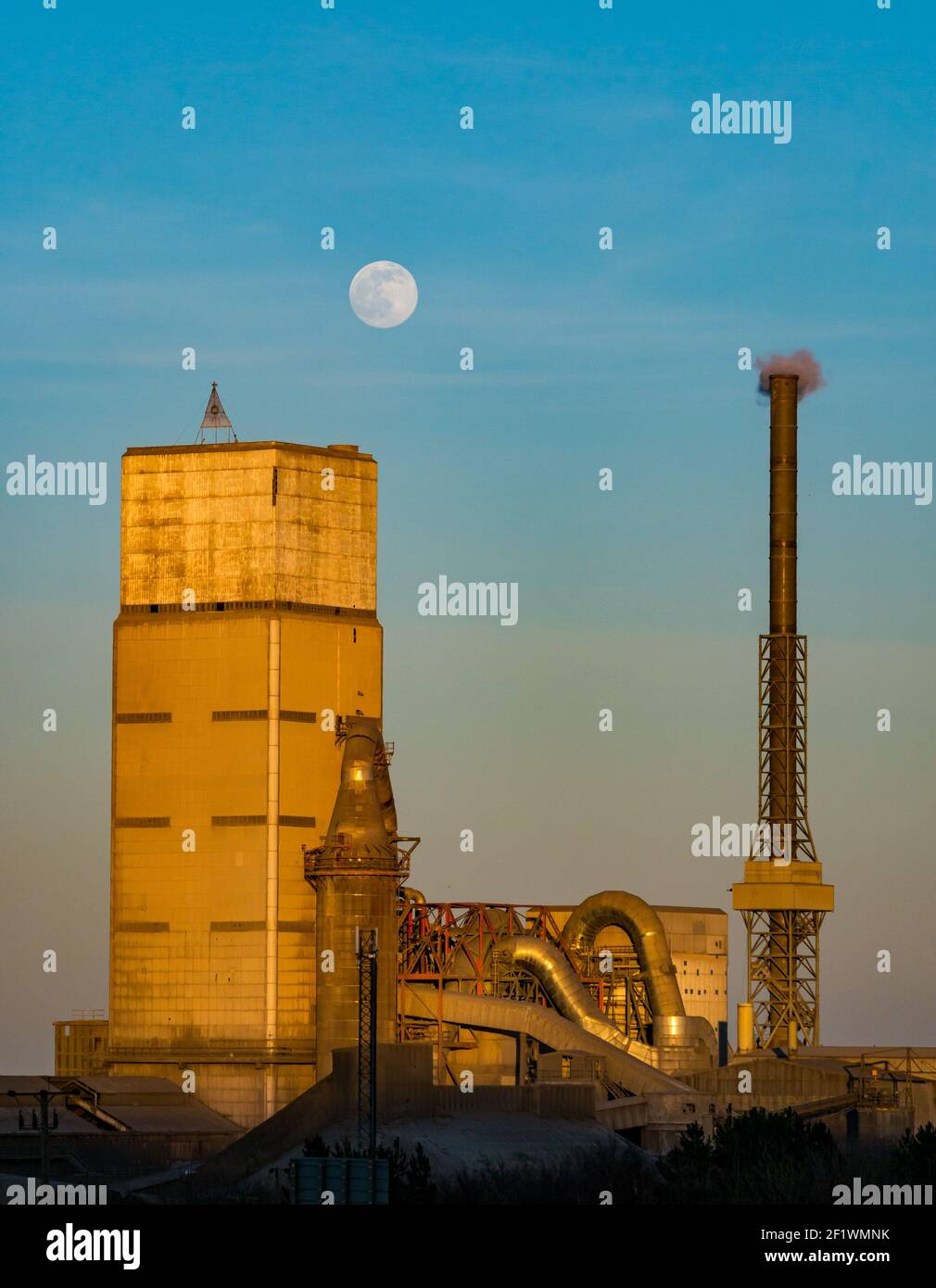 Full snow moon rising over industrial tower at sunset, Dunbar cement ...