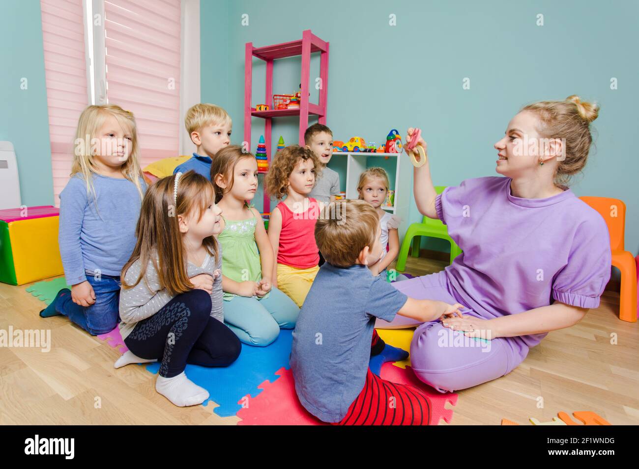 Lovely preschoolers listening young teacher very carefully Stock Photo ...